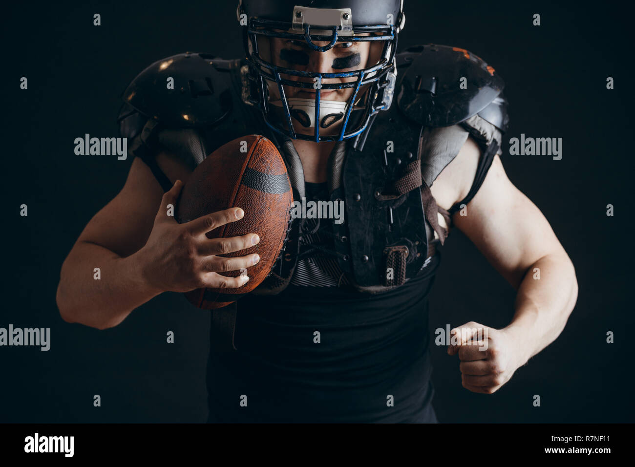 American football player with ball wearing helmet and protective ...