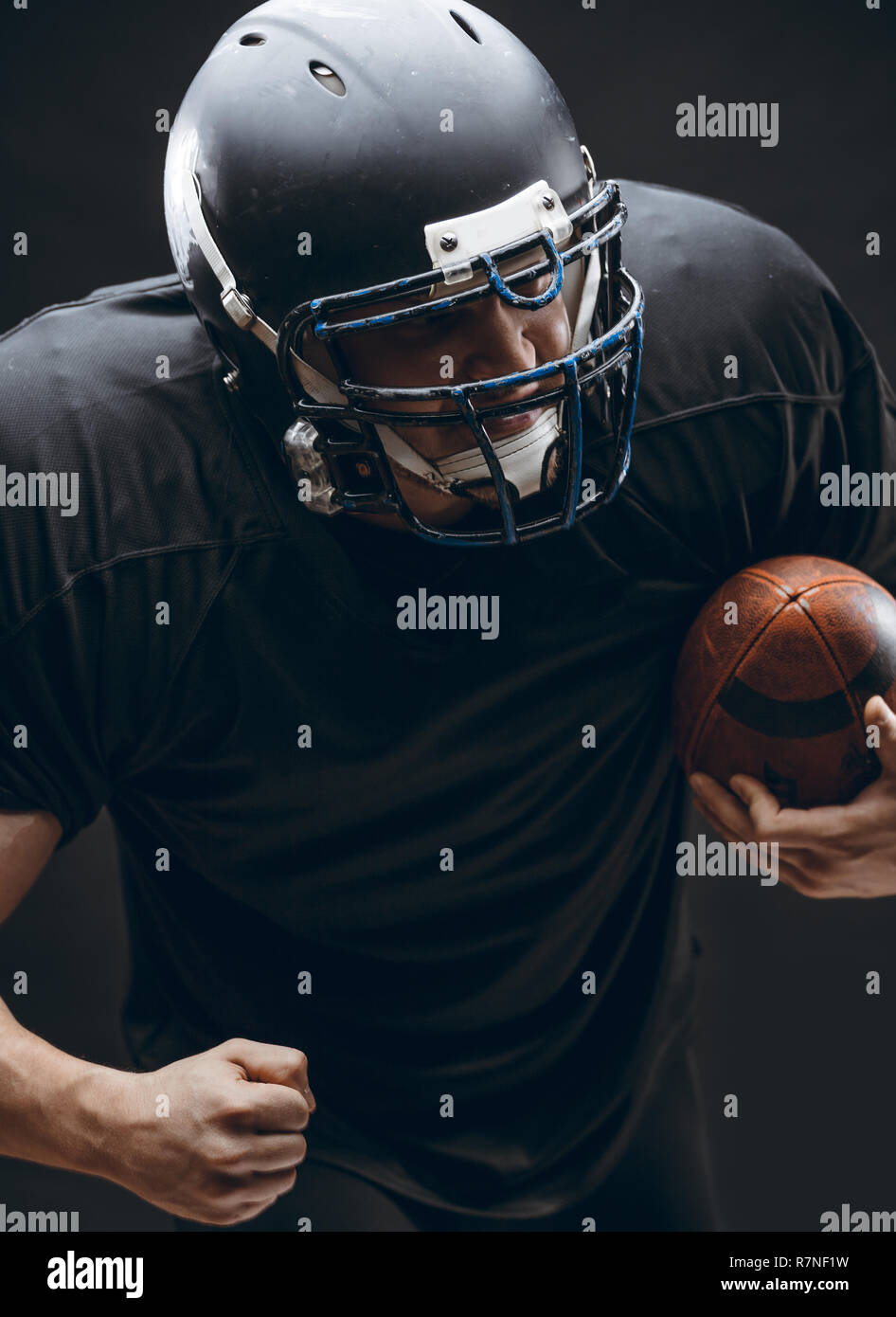 American football player with helmet and armour with a ball against ...