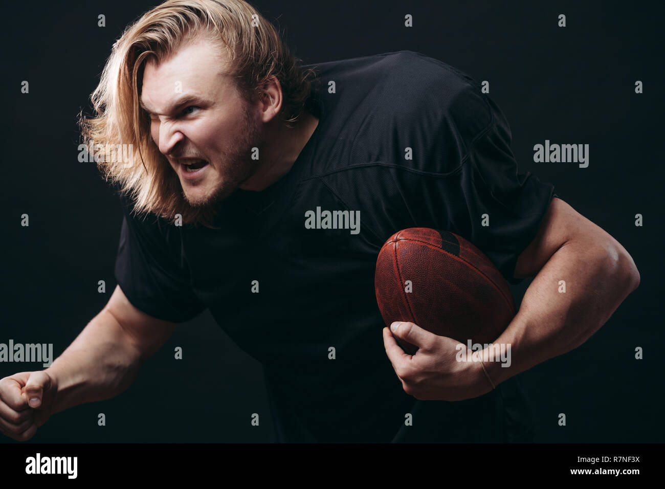 Determined American football player in action isolated on black ...