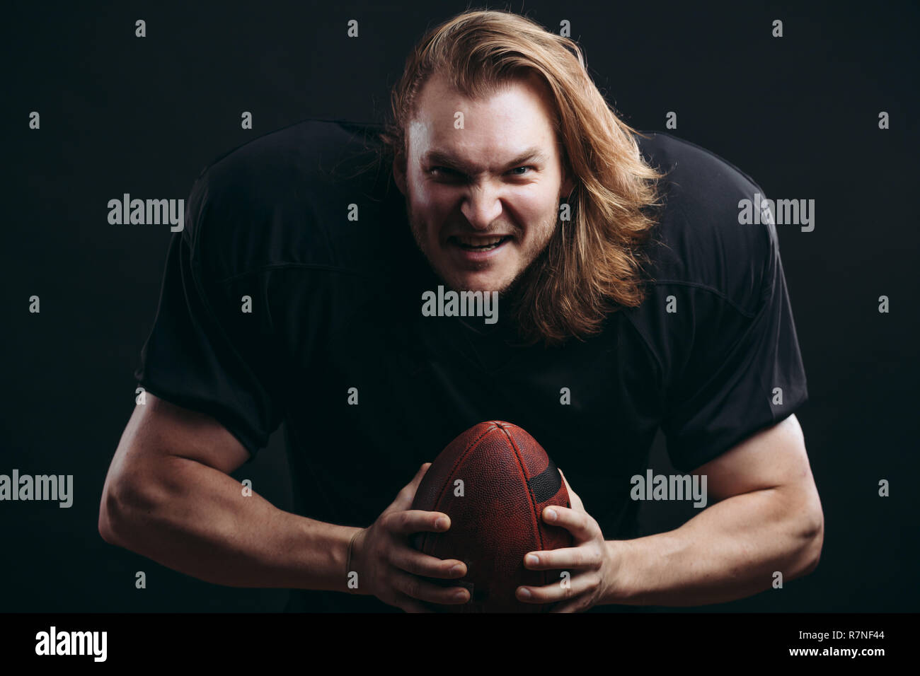 Determined American football player in action isolated on black ...