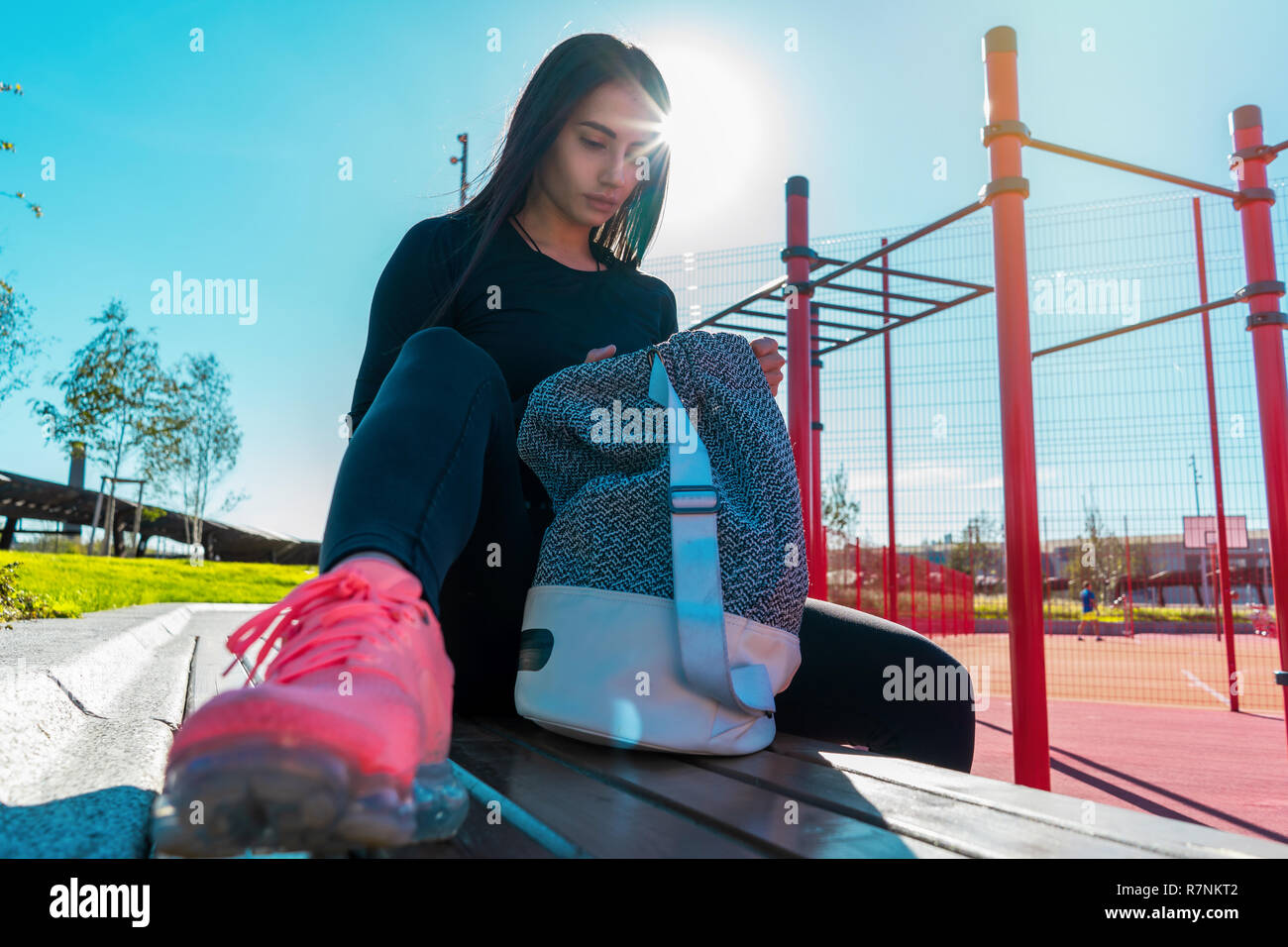 Fitness woman rummaging in her backpack after exercising outdoors in ...