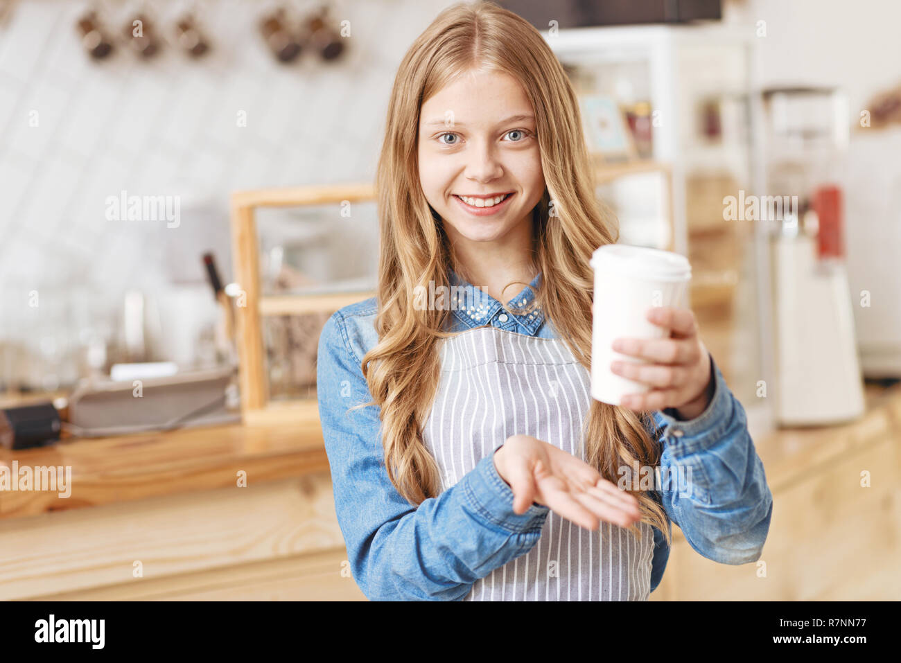 Joyful girl beaming into camera while proposing cup of coffee Stock ...