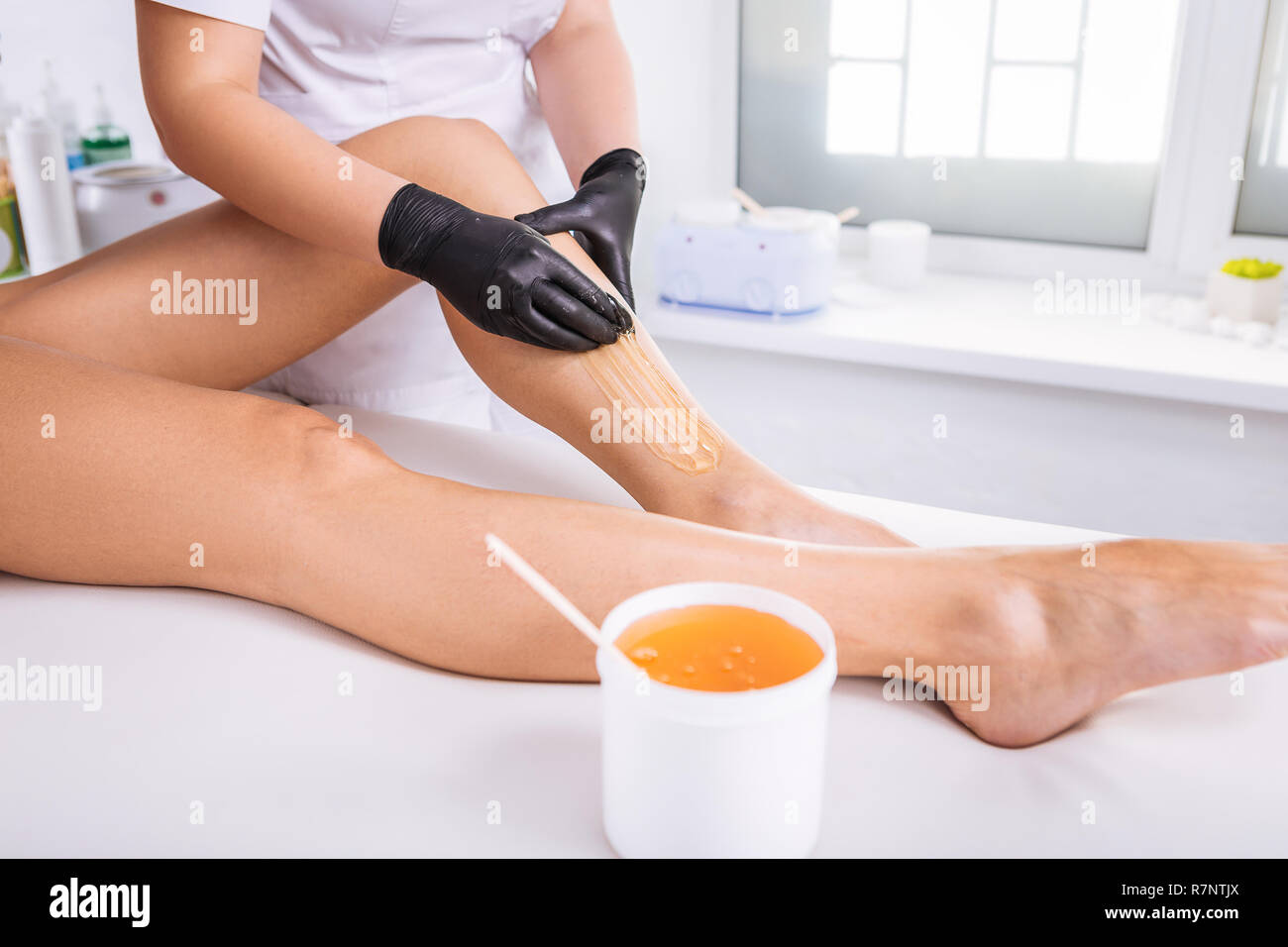 Professional master of wax depilation providing service for client ...