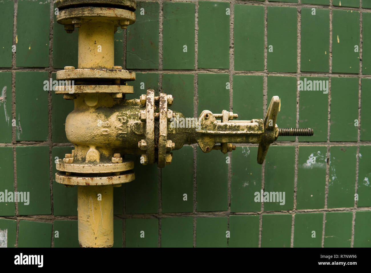 Old weathered gas crane and pipe on the background of a green wall. Old ...