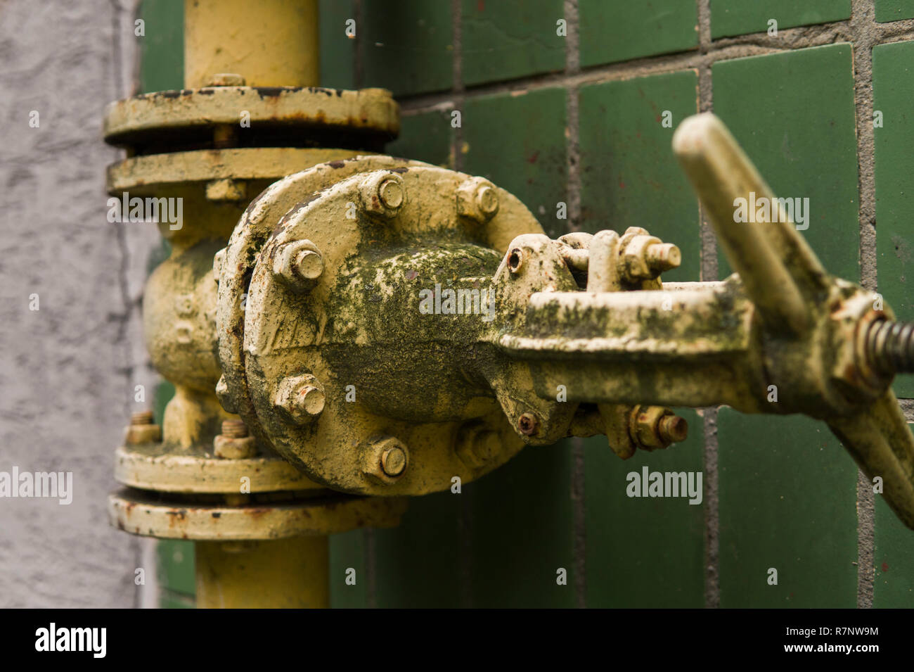 Old weathered gas crane and pipe on the background of a green wall. Old ...