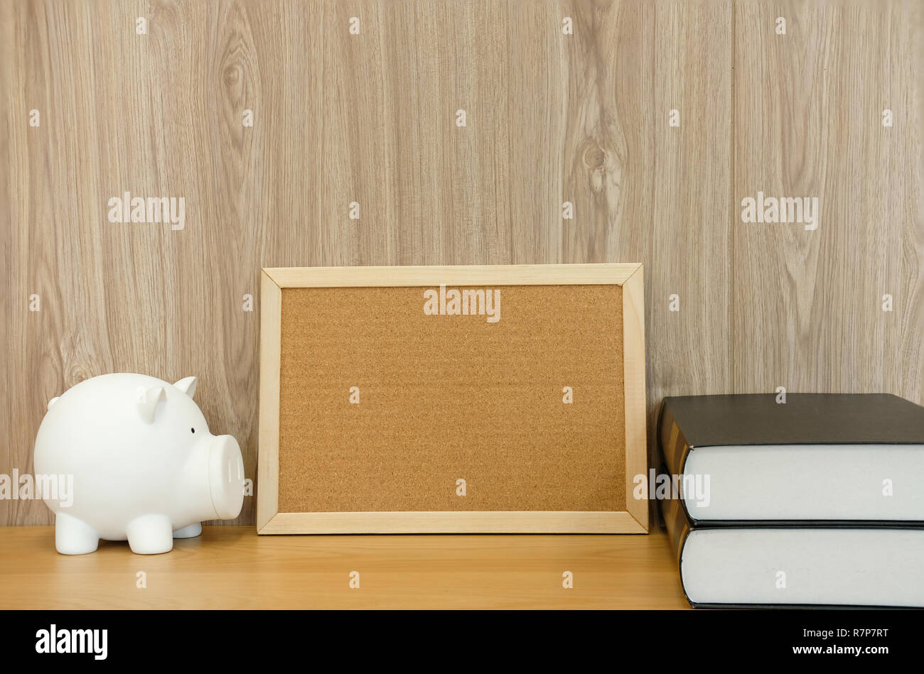 blank cork board piggy bank & book on wooden desk. money saving for ...