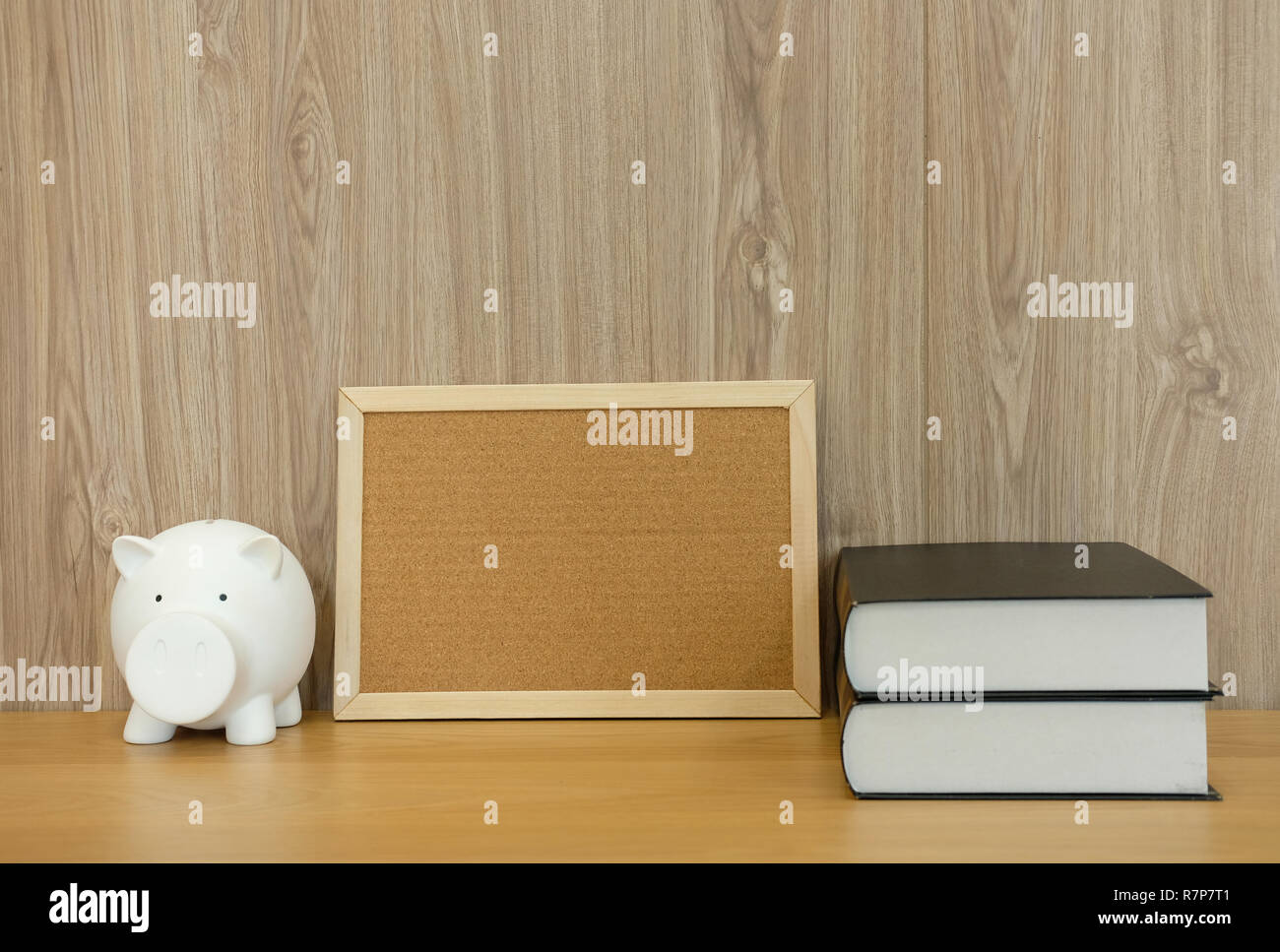 blank cork board piggy bank & book on wooden desk. money saving for ...
