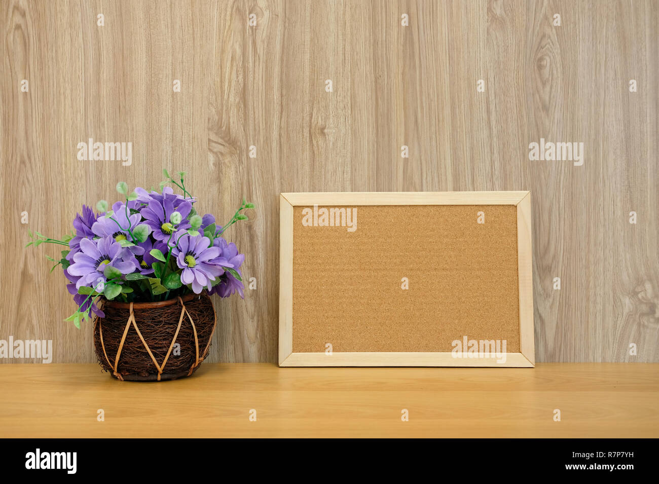 cork board purple artificial flower on wooden table at office workplace ...