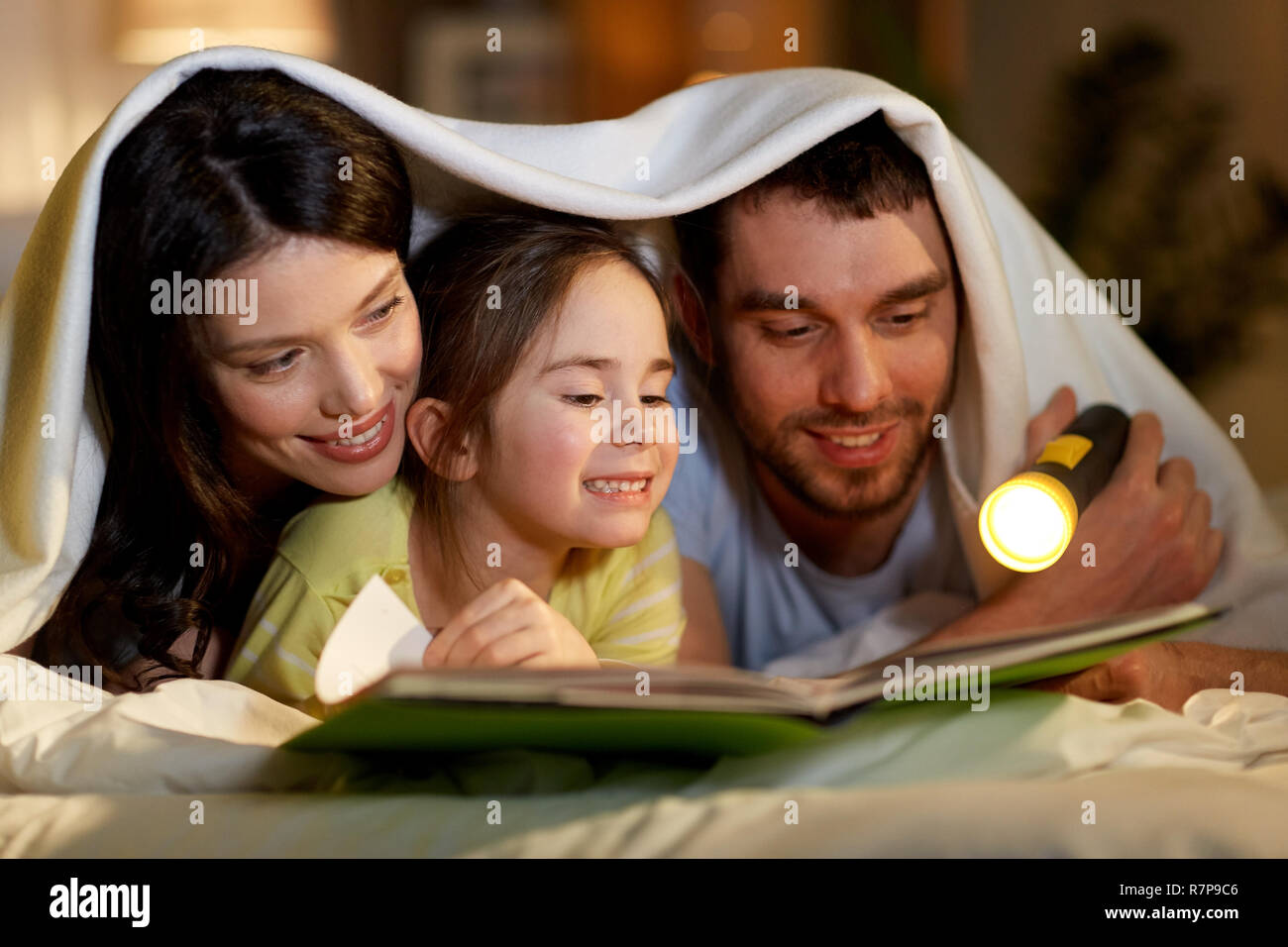 happy family reading book in bed at night at home Stock Photo - Alamy
