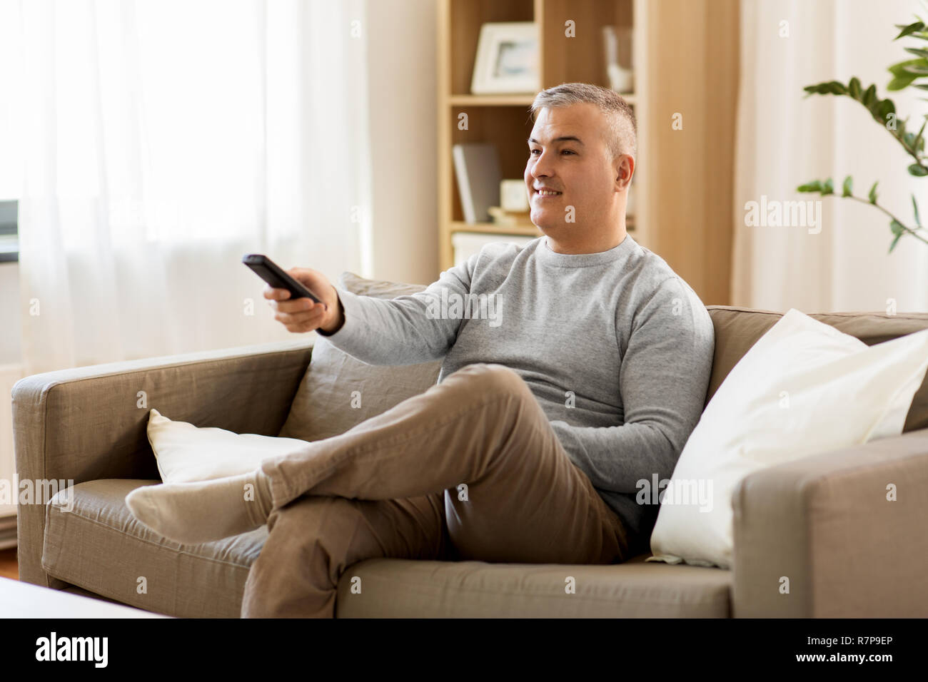man with remote control watching tv at home Stock Photo - Alamy
