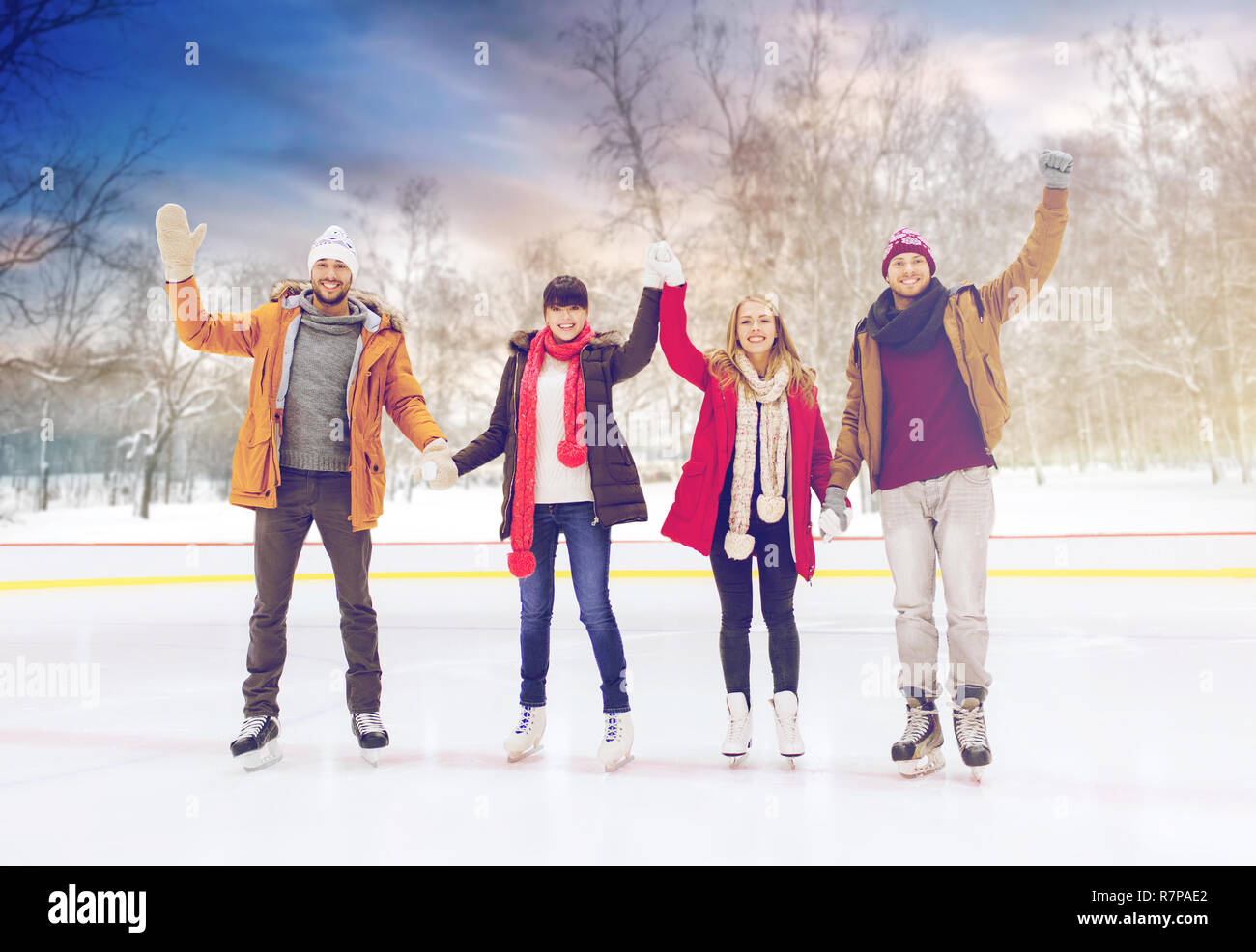 happy friends waving hands on skating rink Stock Photo - Alamy