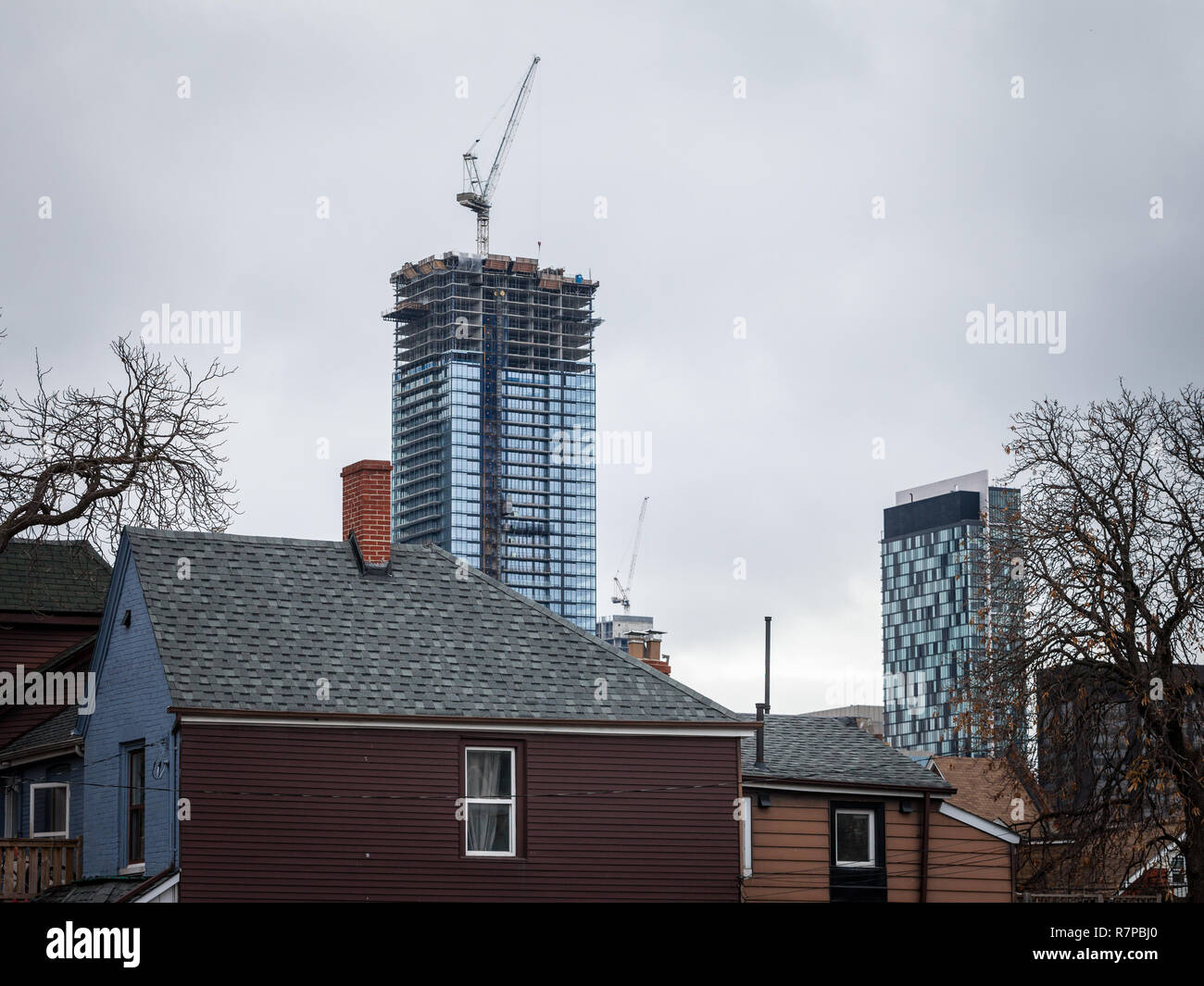 Condo skyscraper construction site with its cranes while smaller houses ...