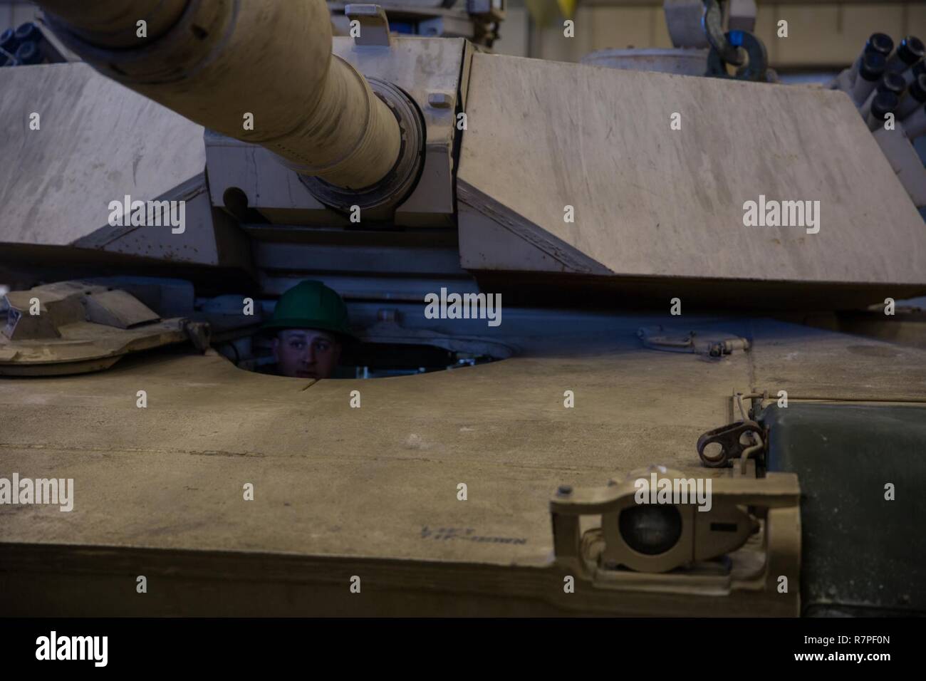 A Marine climbs inside an M1A1 Abrams tank to properly fasten its 120mm ...