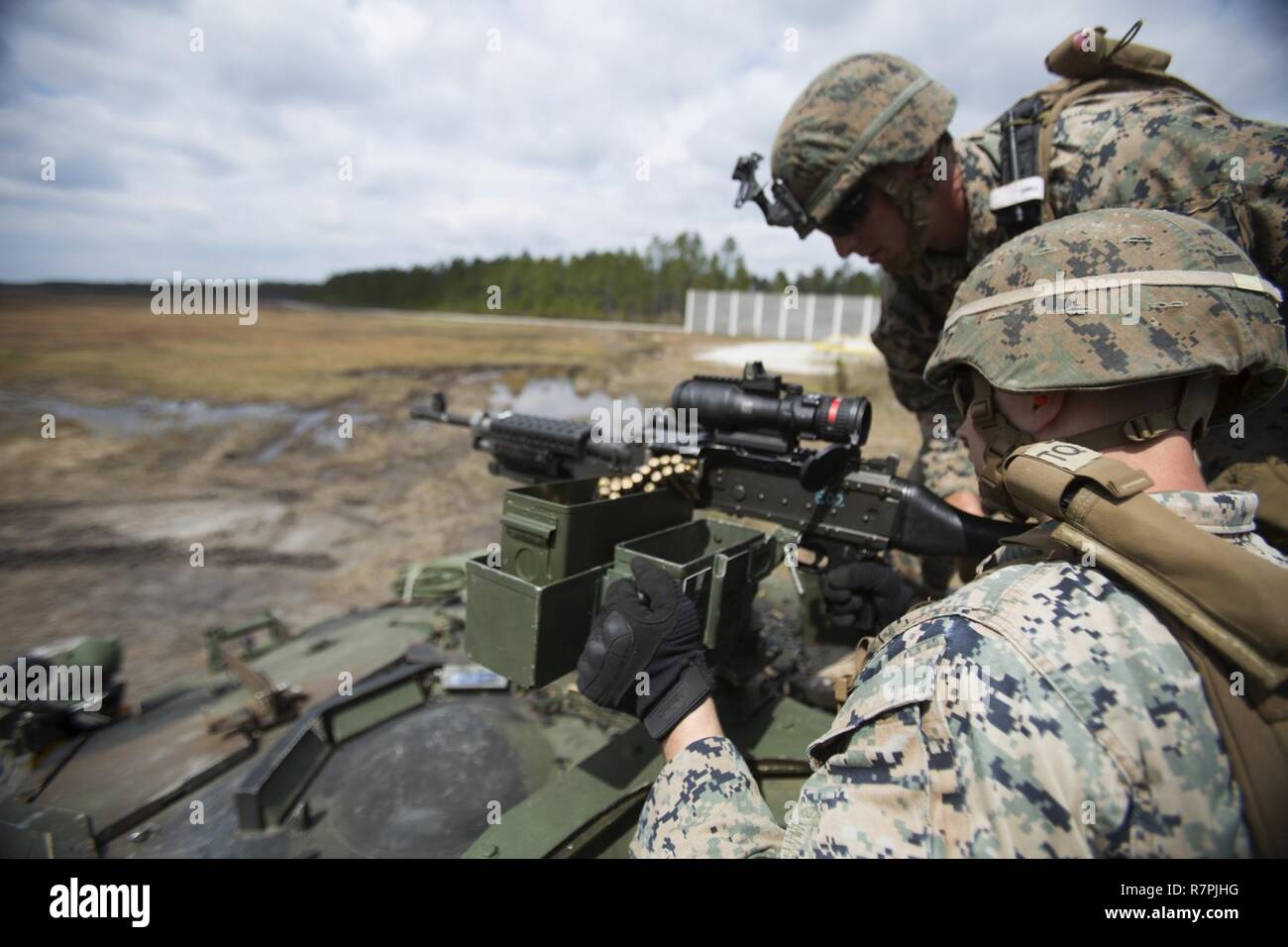 A Marine handles an M240B machine gun while a position safety officer ...