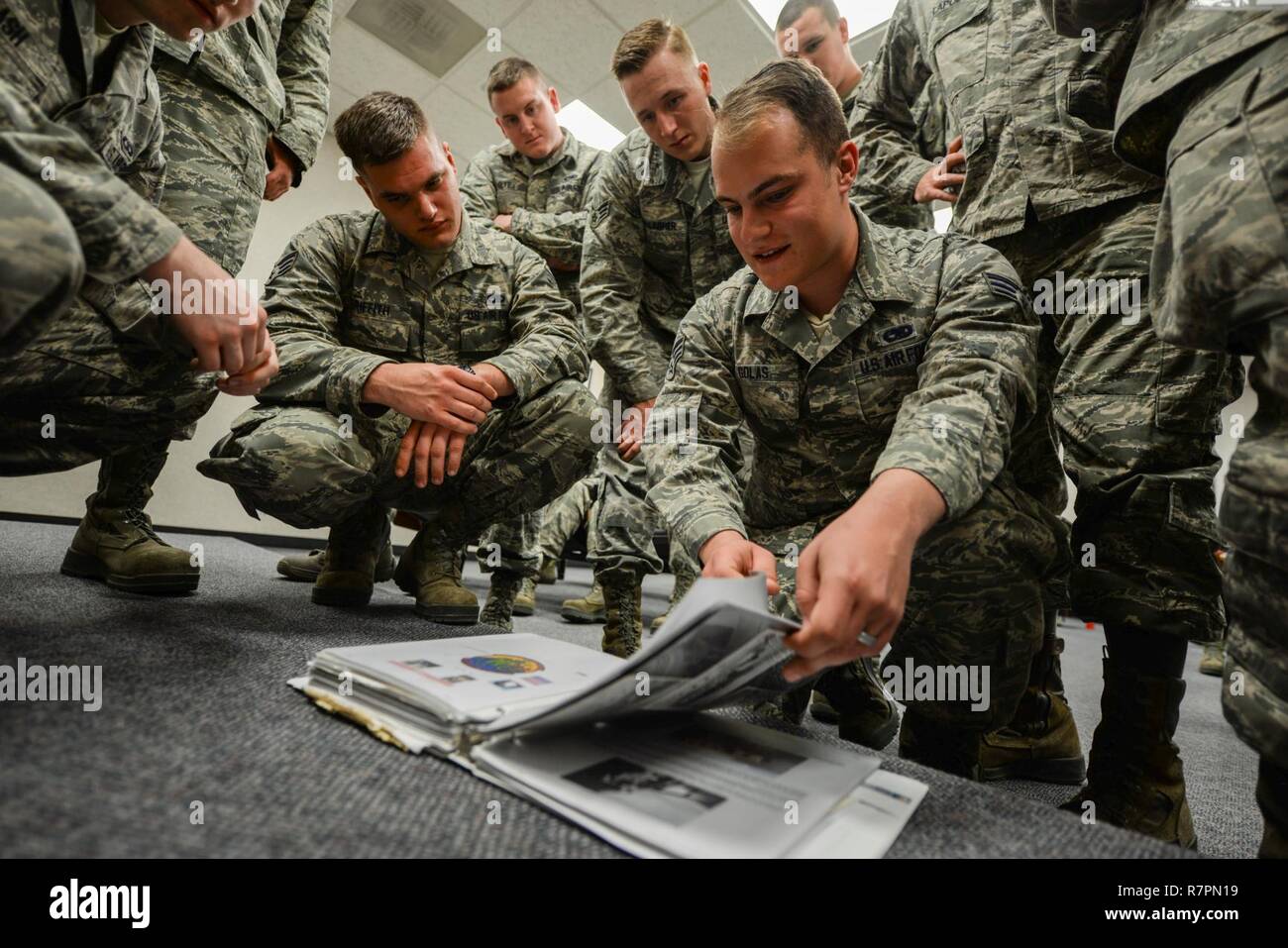 Airmen huddle around a binder full of Air Force heritage pictures and ...