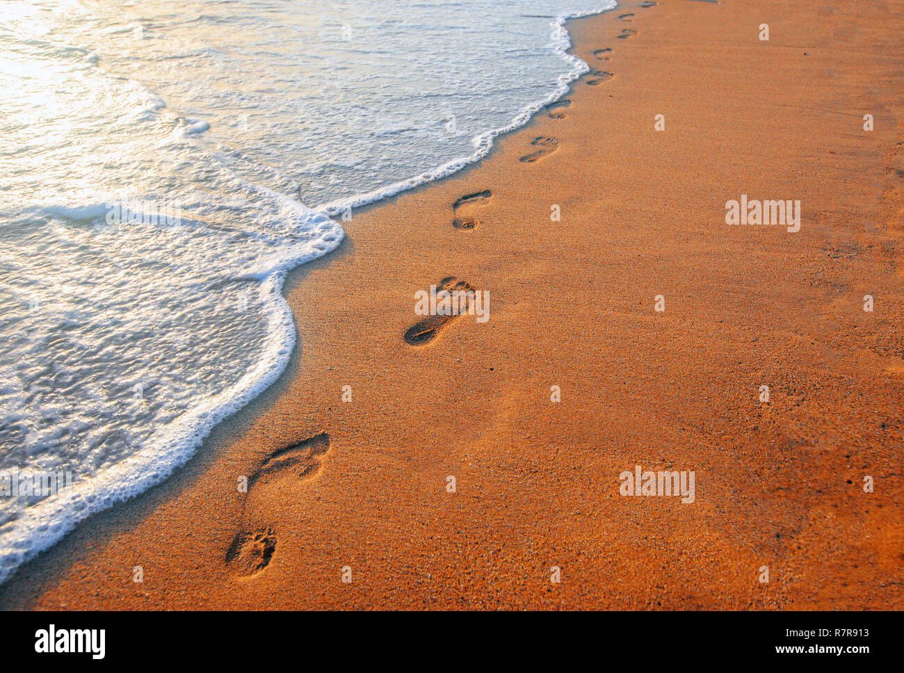 beach, wave and footprints at sunset time Stock Photo - Alamy