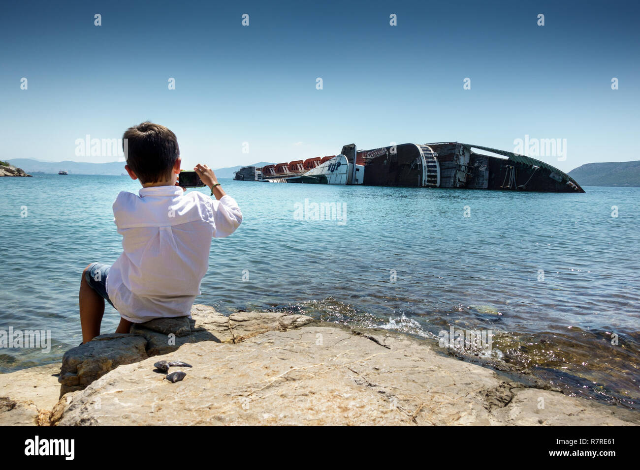 Boy photographing sinking ship Stock Photo - Alamy