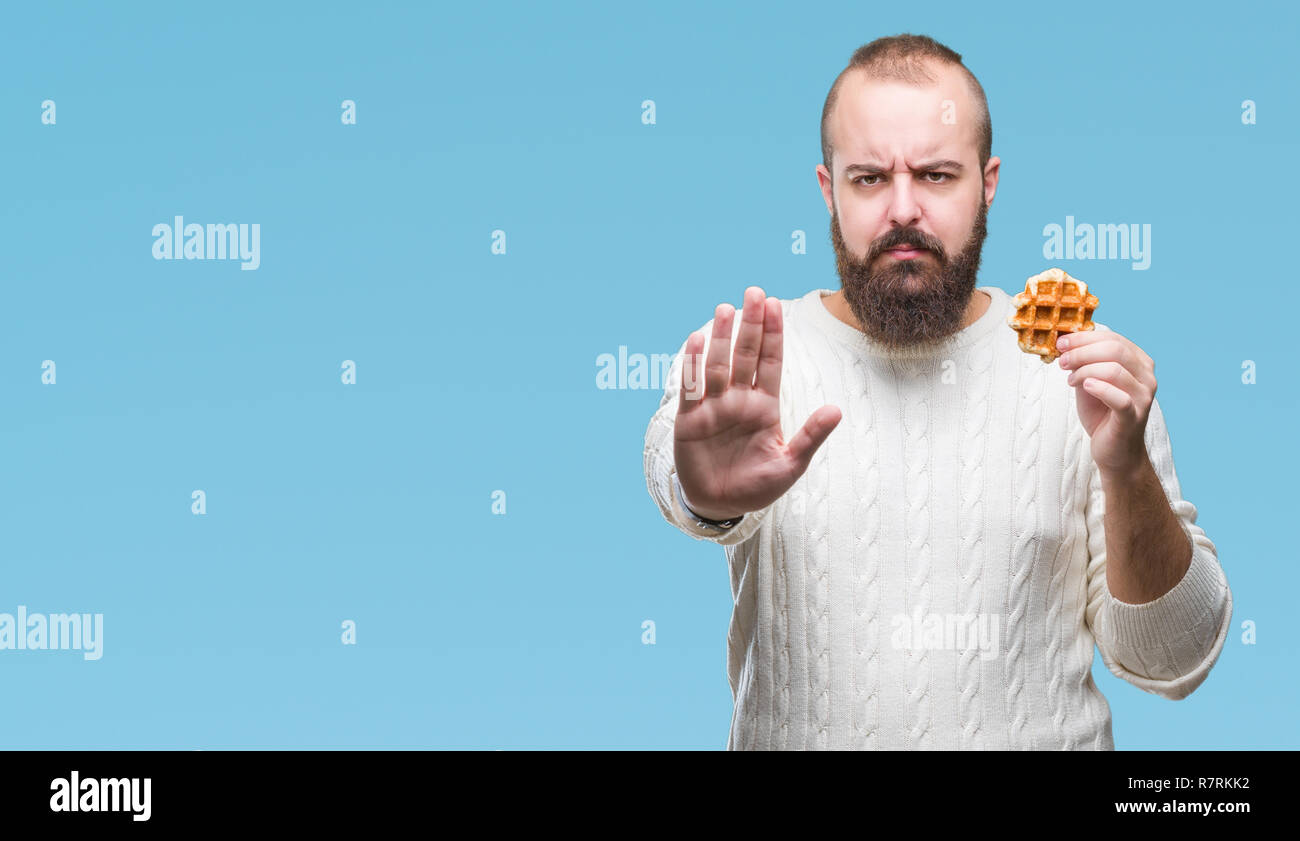 Young caucasian hipster man eating sweet waffle over isolated ...