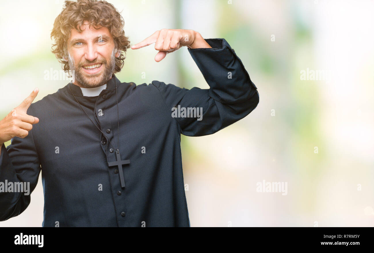 Handsome hispanic catholic priest man over isolated background smiling ...