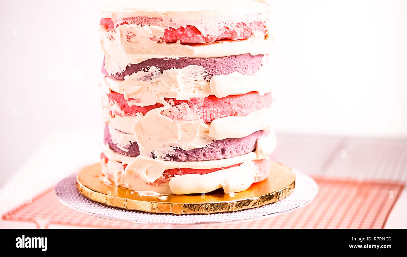 Baker frosting pink and purple cake with a white buttercream icing ...