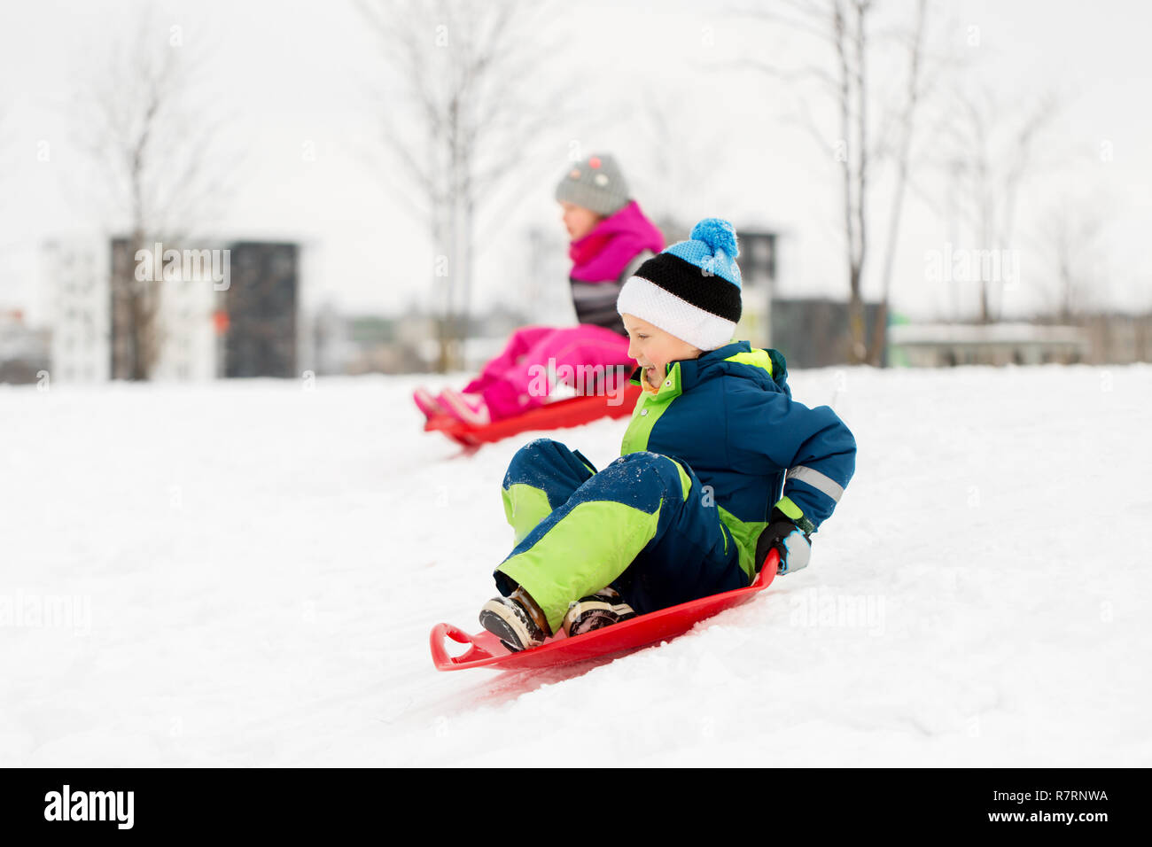 kids sliding on sleds down snow hill in winter Stock Photo - Alamy