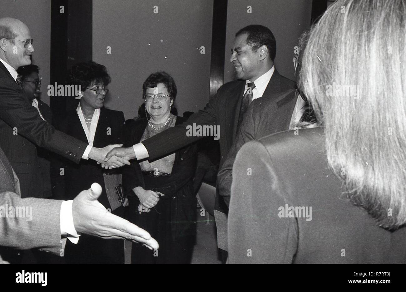 men shaking hands women standing around Stock Photo - Alamy