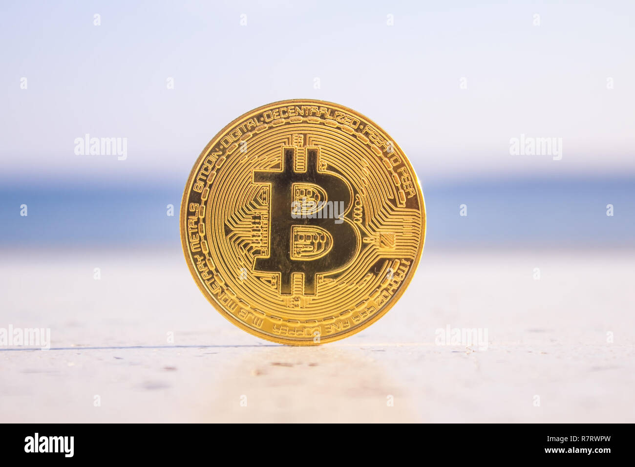 Golden bitcoin coin on beach as background with blue sky and Red Sea ...