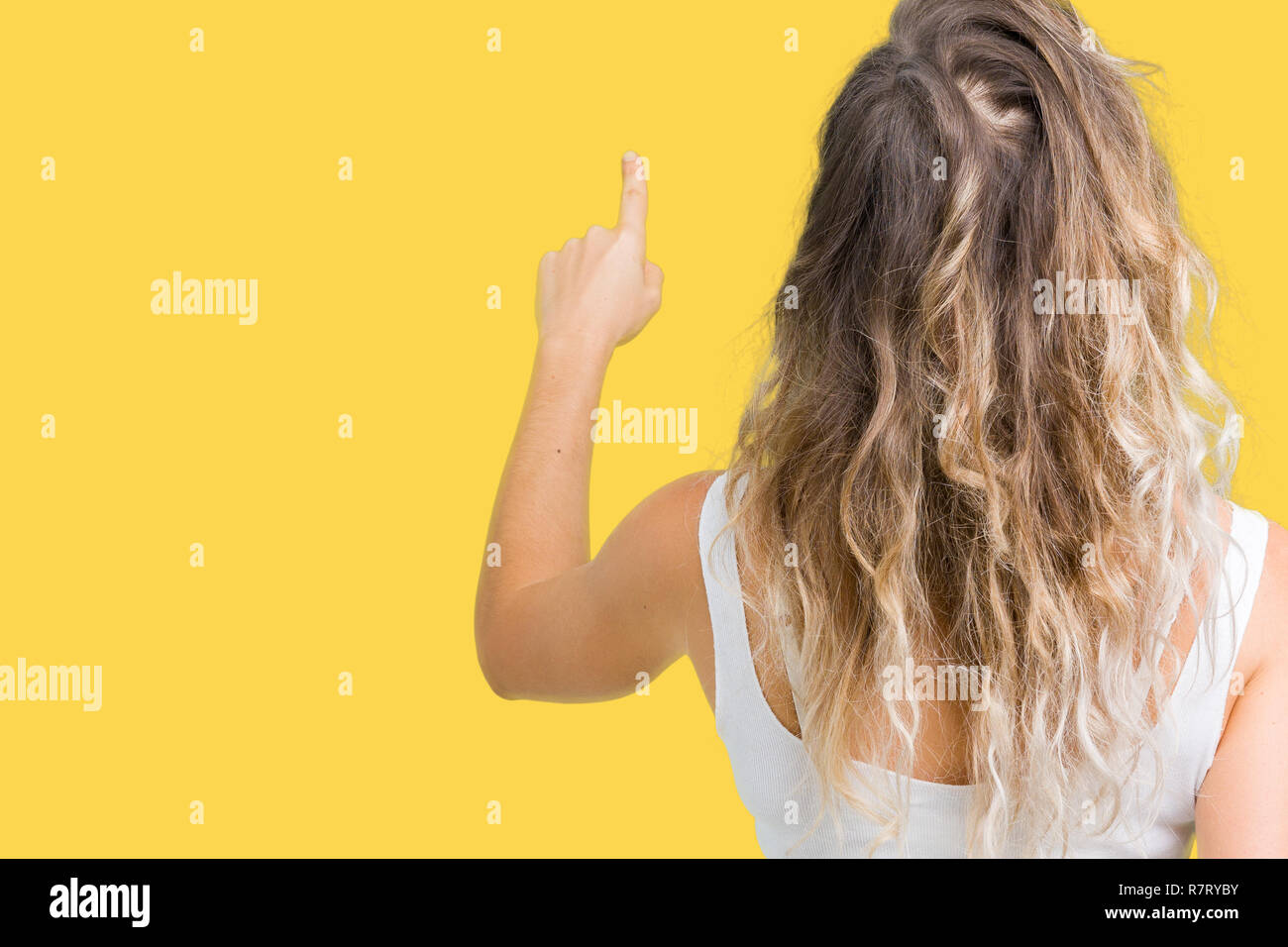 Beautiful young blonde woman over isolated background Posing backwards ...