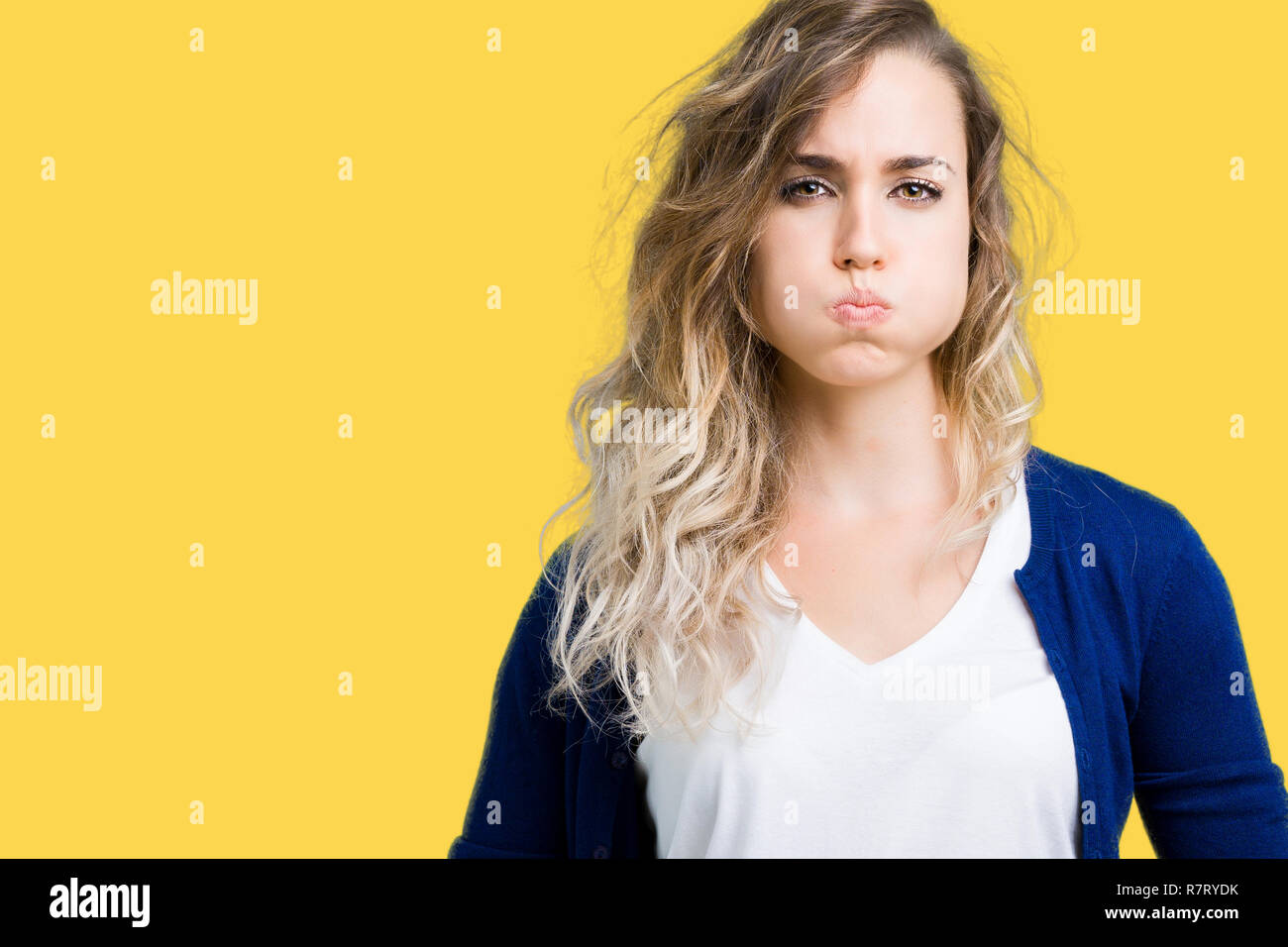 Beautiful young blonde woman over isolated background puffing cheeks ...