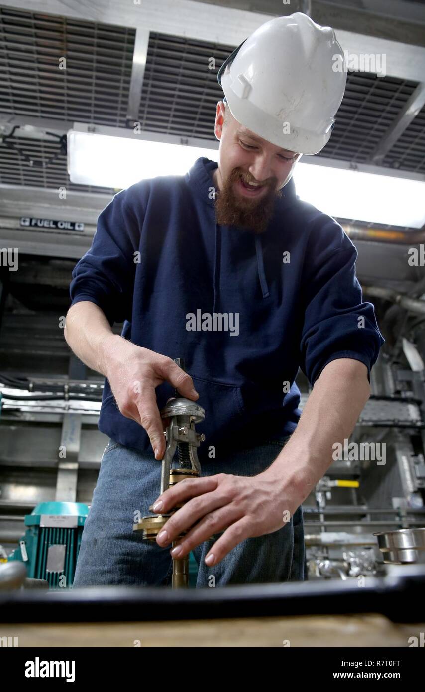 Justin Langan, USNS Trenton third engineer, reassembles a fuel filter ...