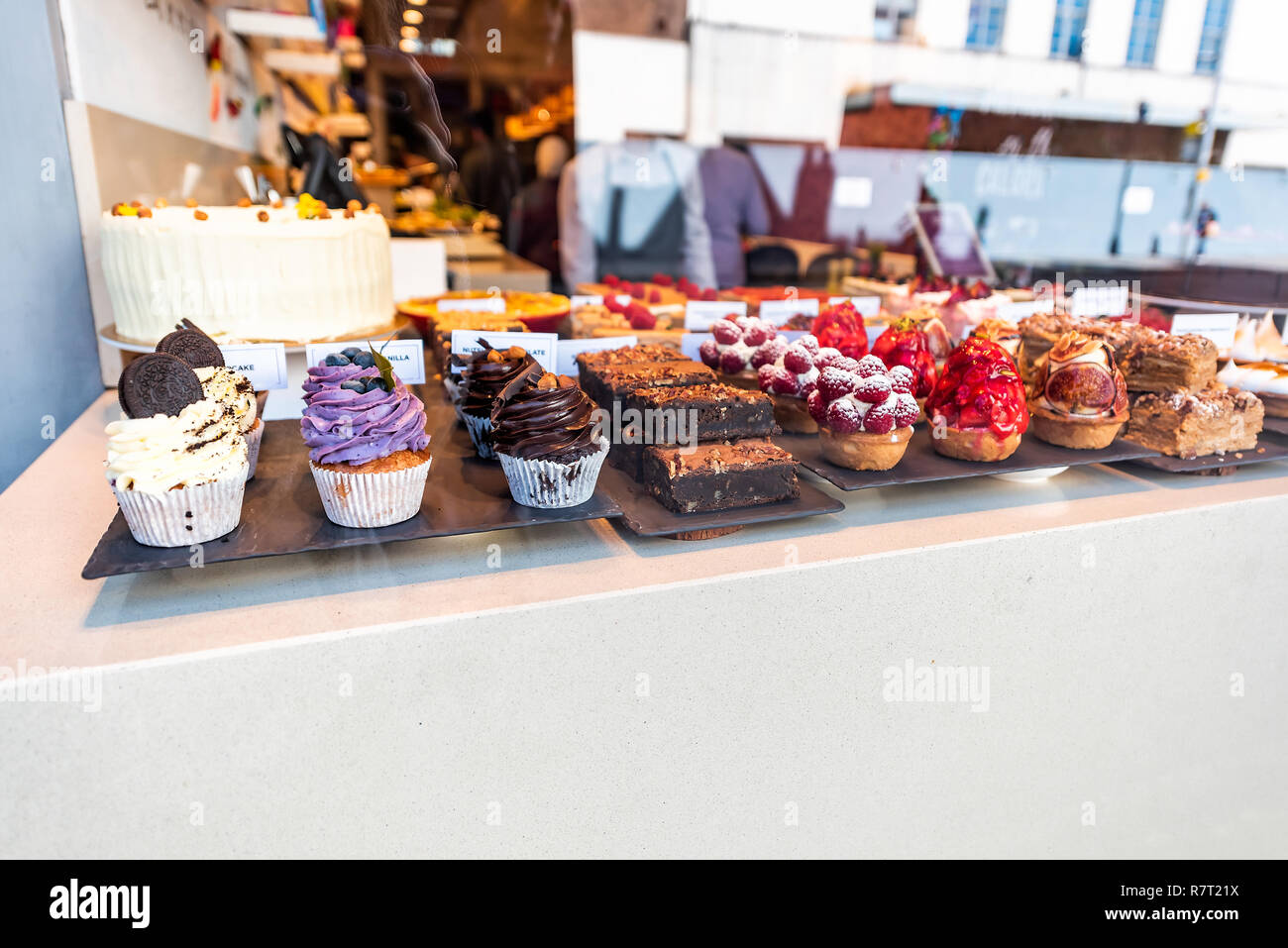 Window display of many chocolate cupcakes, brownies, tarts stuffed with ...