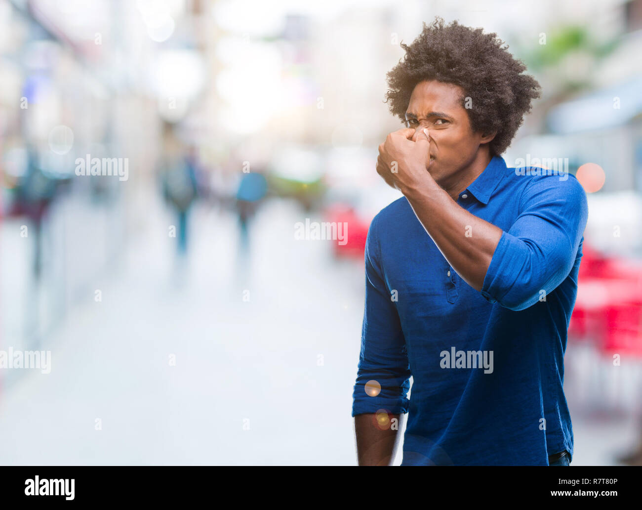 Afro american man over isolated background smelling something stinky ...