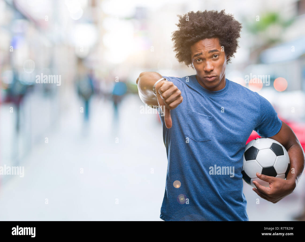 Afro american man holding football ball over isolated background with ...