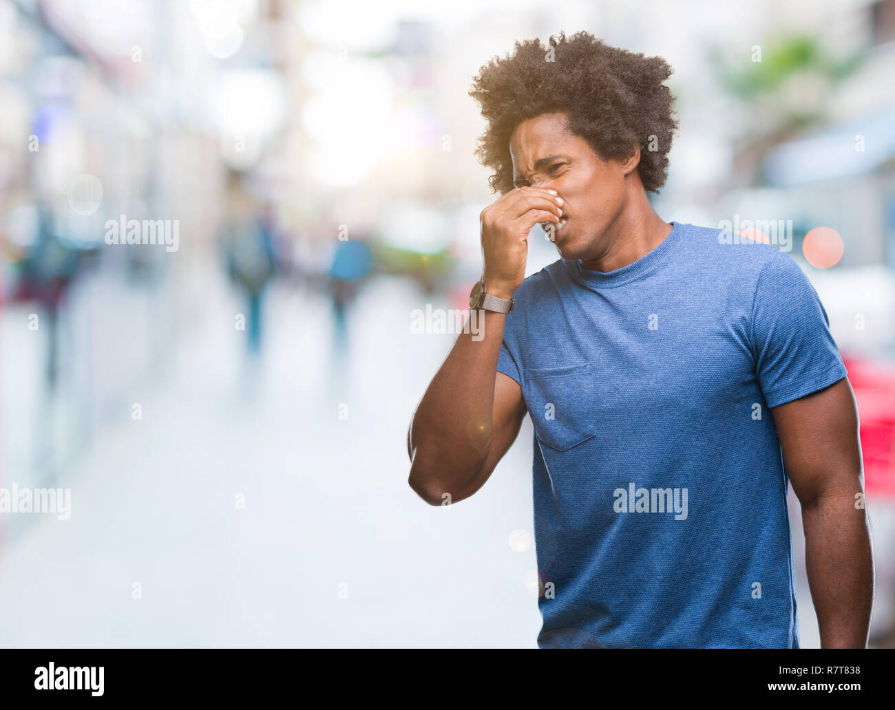 Afro american man over isolated background smelling something stinky ...