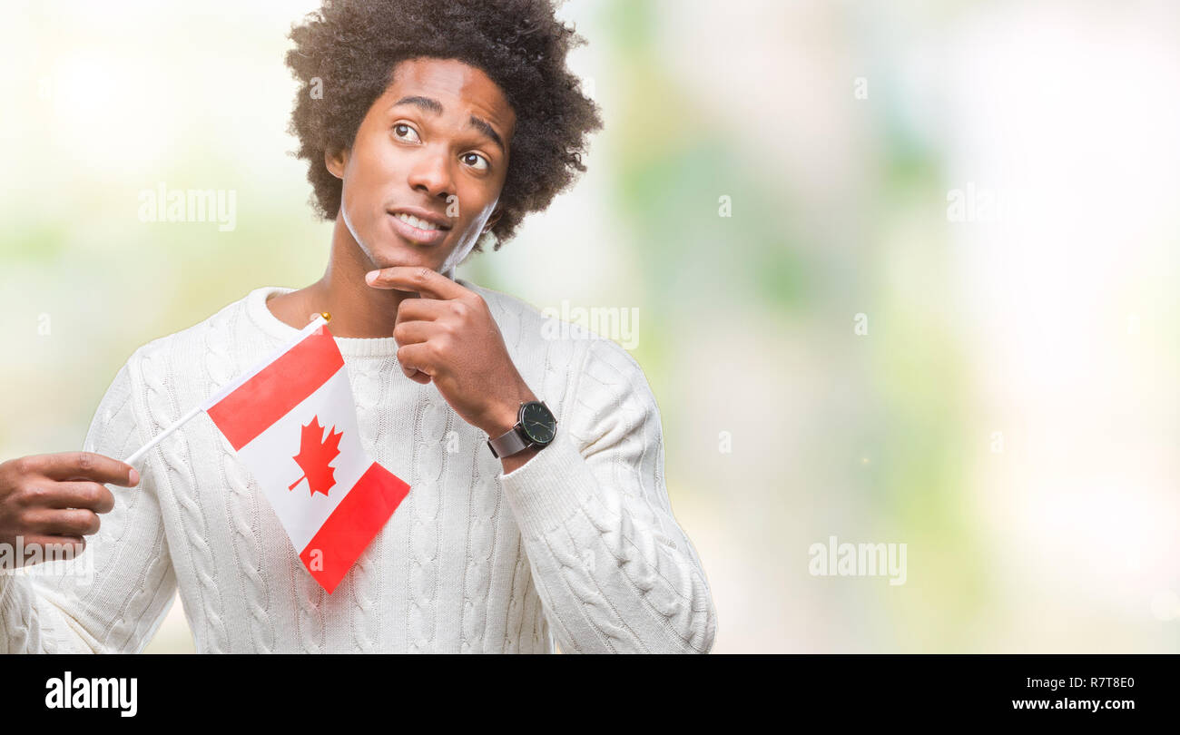 Afro american man flag of Canada over isolated background serious face ...