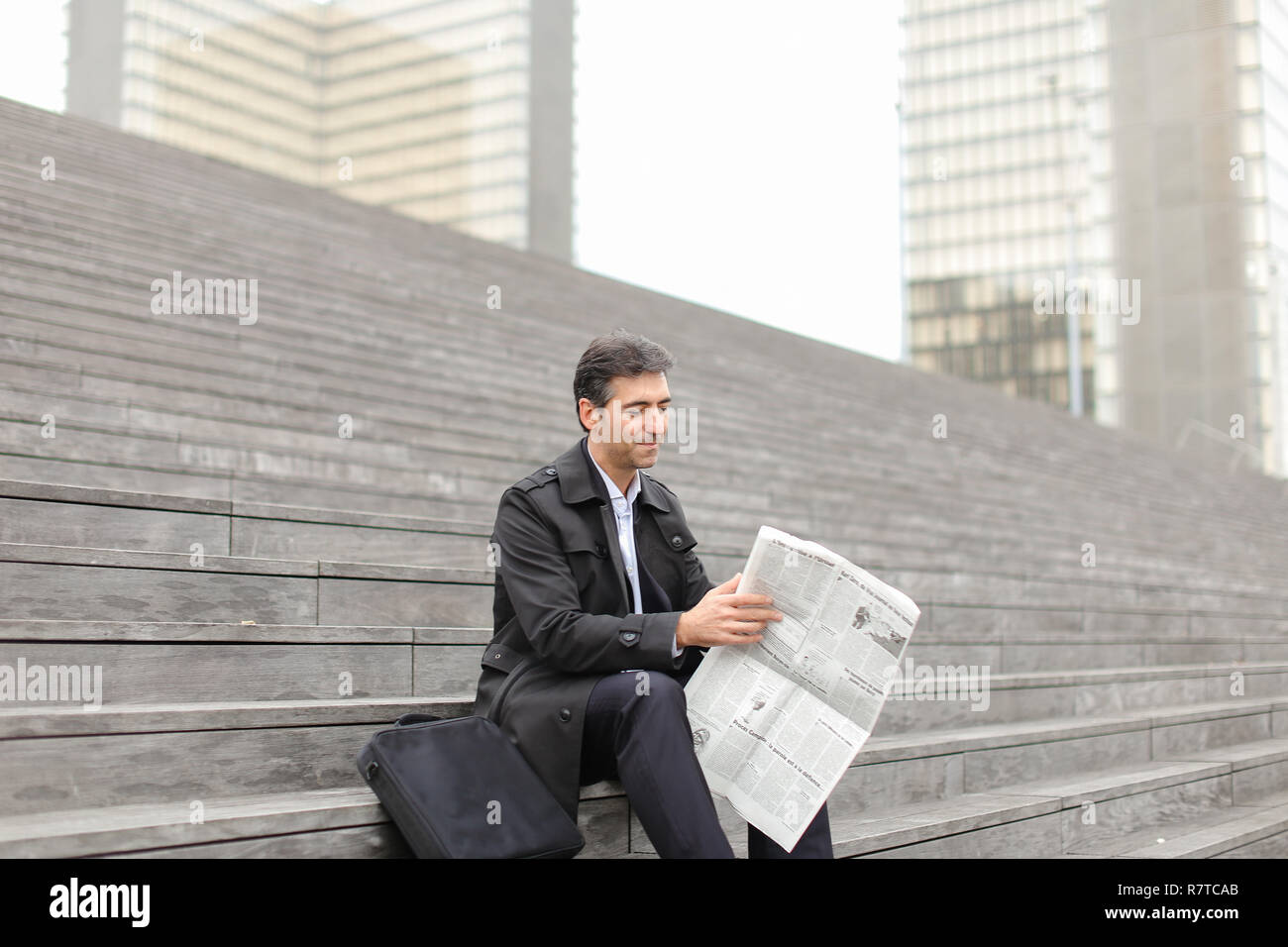male business tutor sitting on stairs and reading newspaper Stock Photo ...
