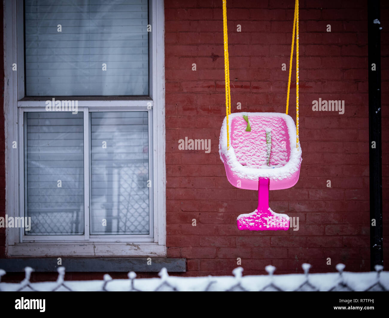 Pink swing in the snow Stock Photo - Alamy