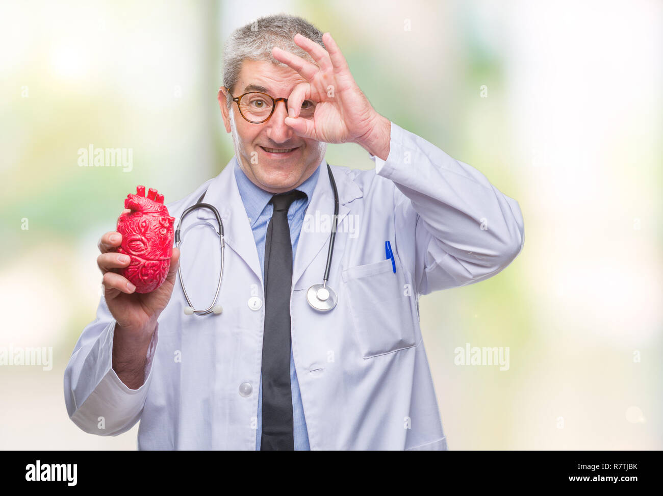 Handsome senior cardiologist doctor man holding heart over isolated ...