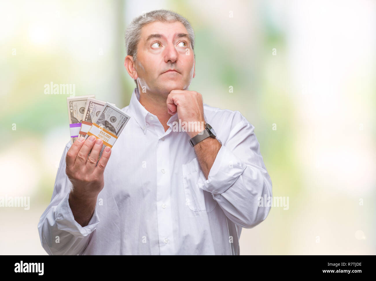 Handsome senior man holding bunch of money over isolated background ...