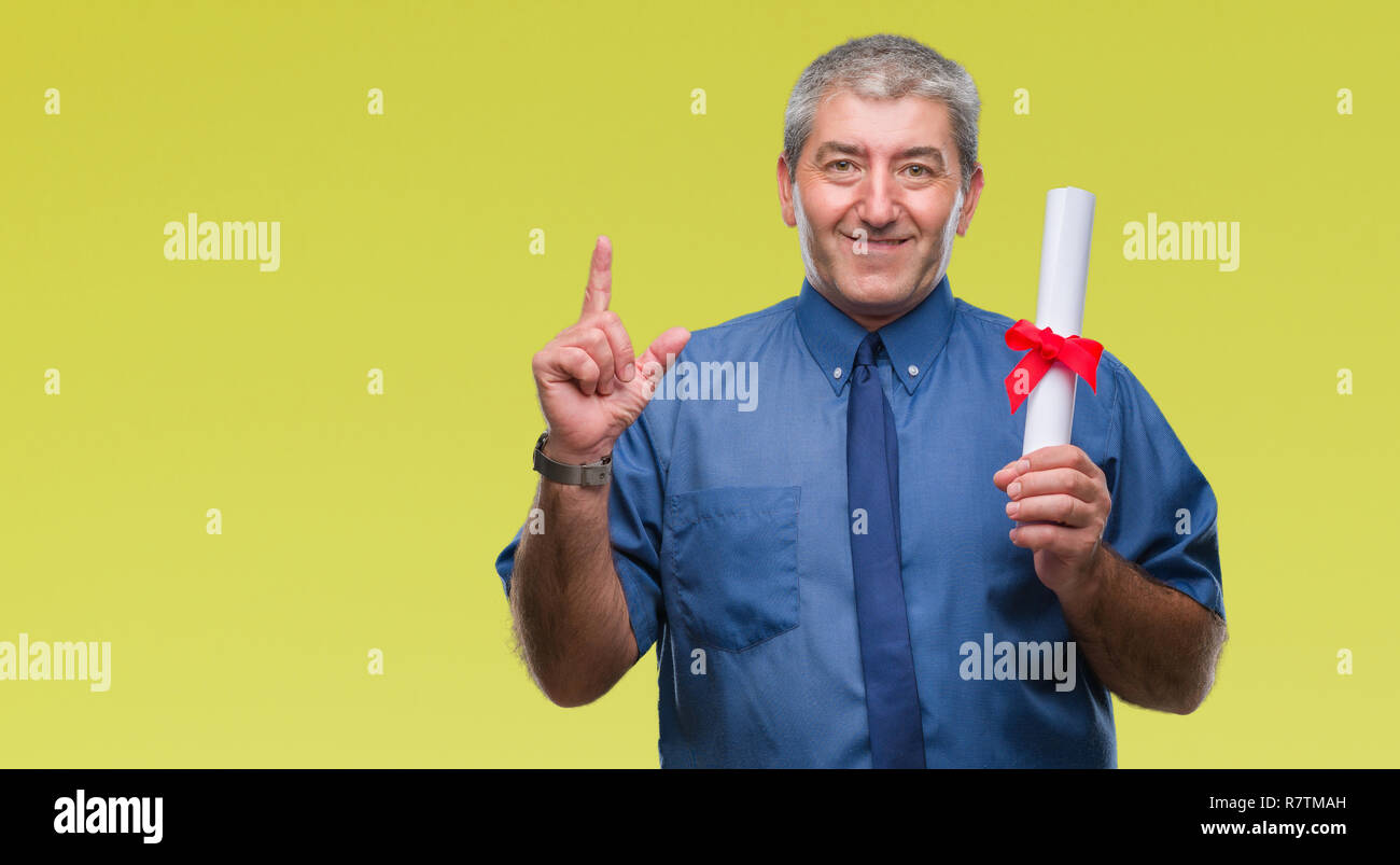 Handsome senior man holding degree over isolated background surprised ...