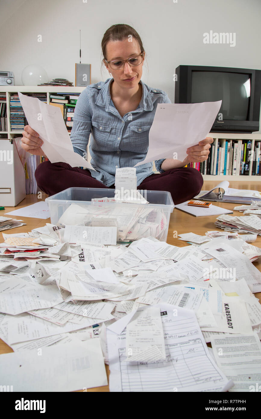 Woman sorting documents, records, invoices and receipts on the ground ...