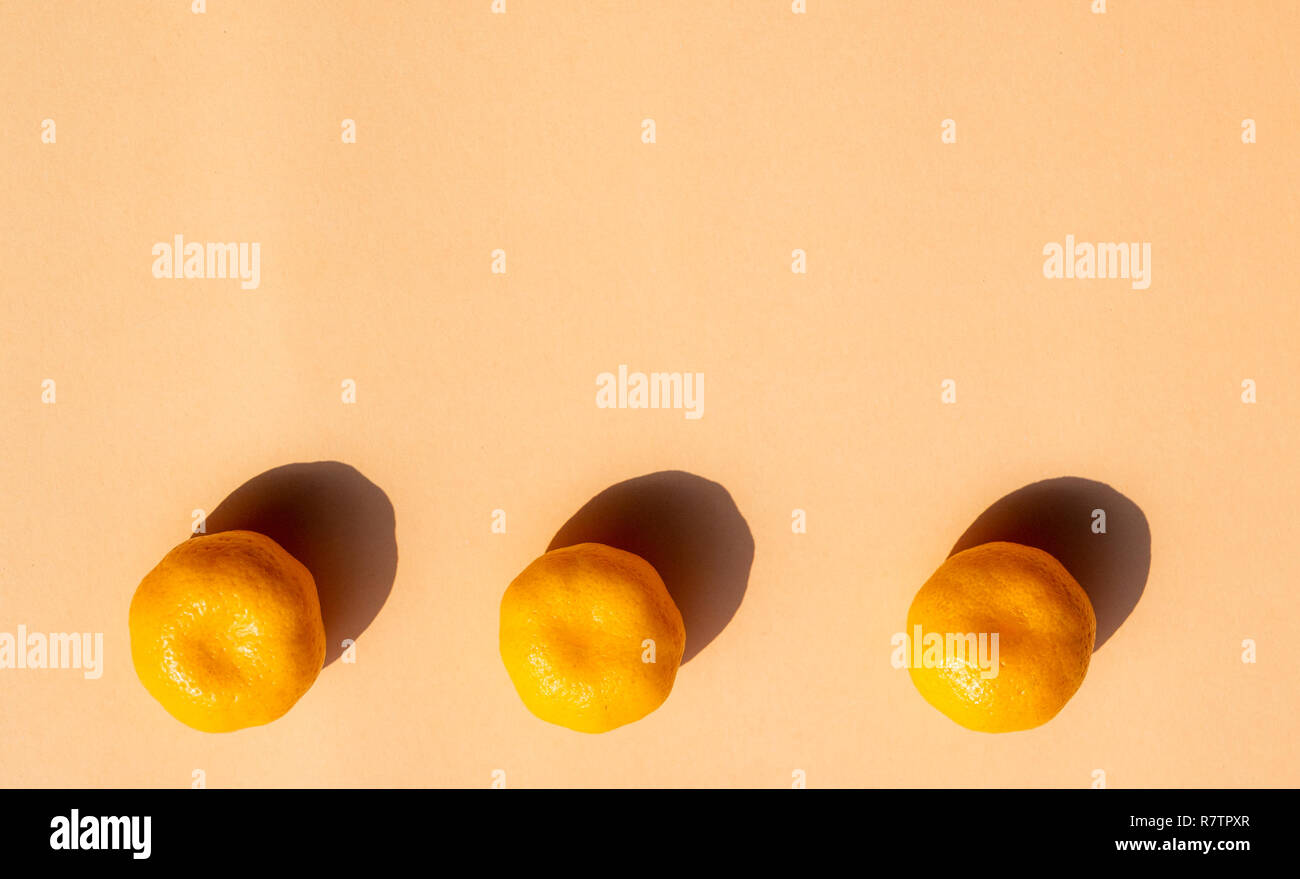 3 whole oranges with strong shadow on orange background, copy space ...