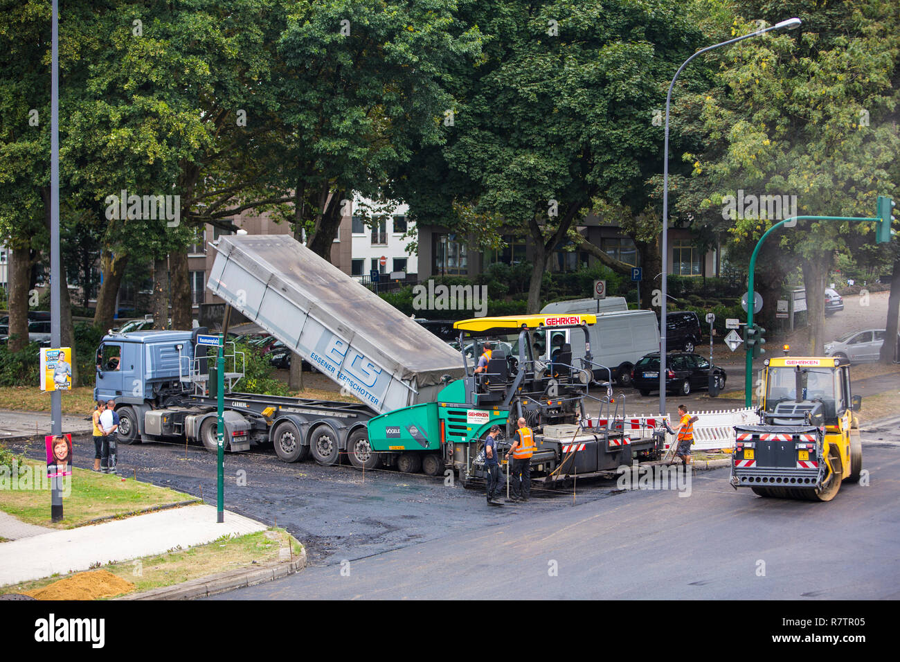 Rolling machine and an asphalt spreader during asphalt work on a large ...