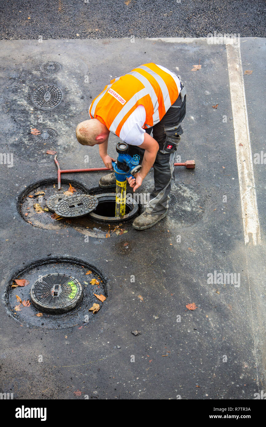 Road construction worker connecting a hydrant for water supply of the ...