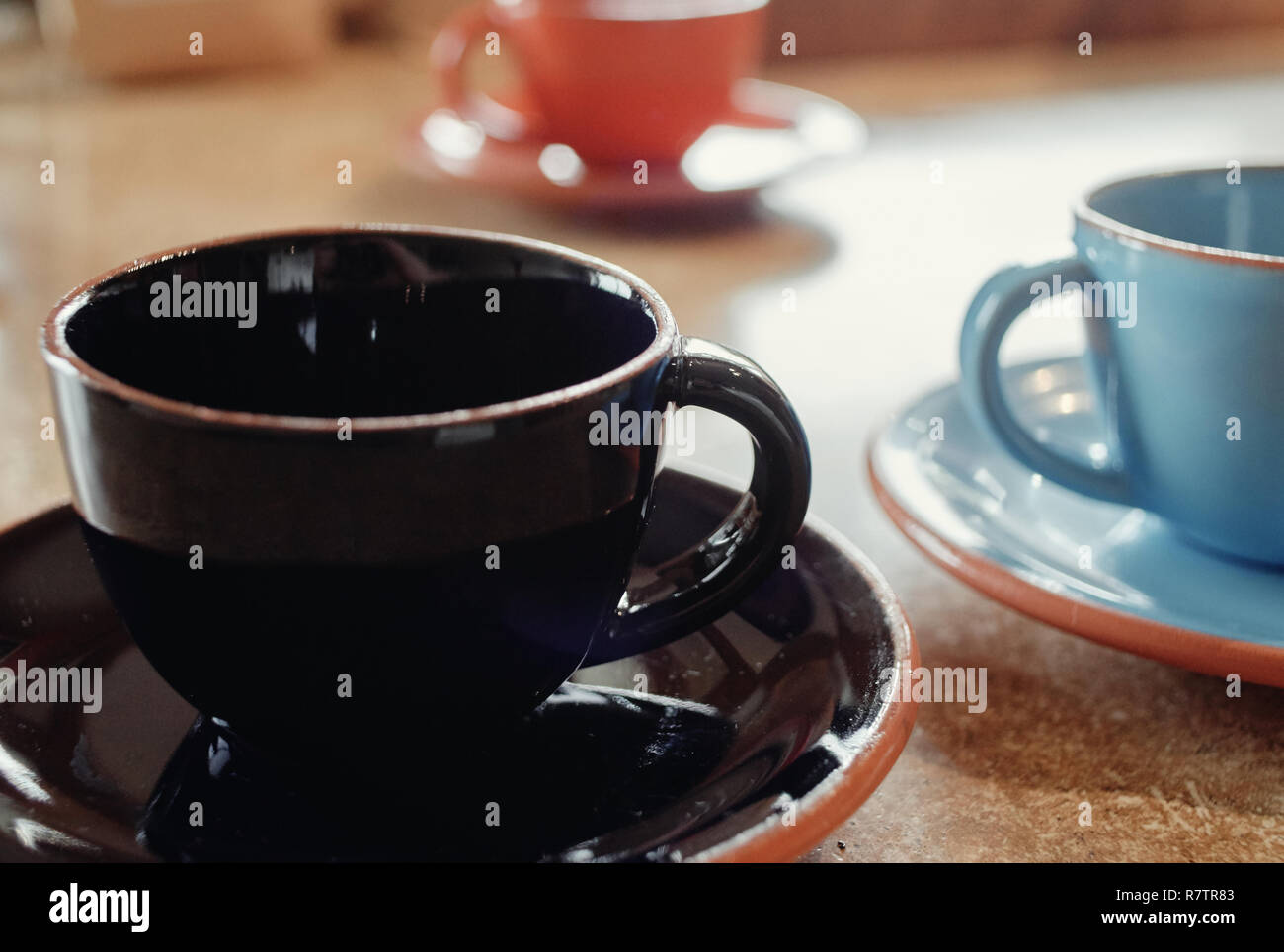 3 coffee cups and saucers brightly lit on table Stock Photo - Alamy