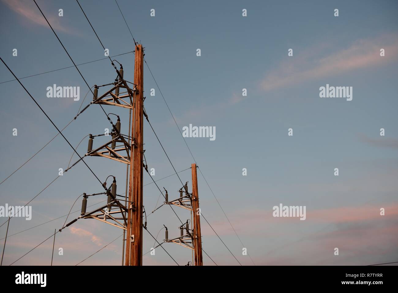 Electrical utility poles and high voltage power lines at sunset in ...