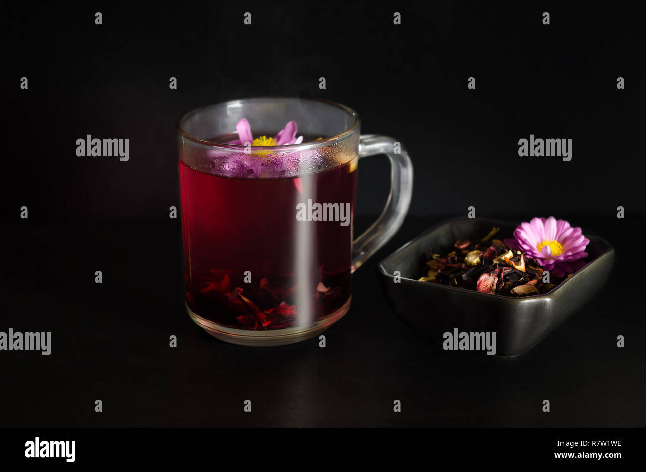 Cup of hibiscus tea with dry fruits on black background. Karkade tea ...