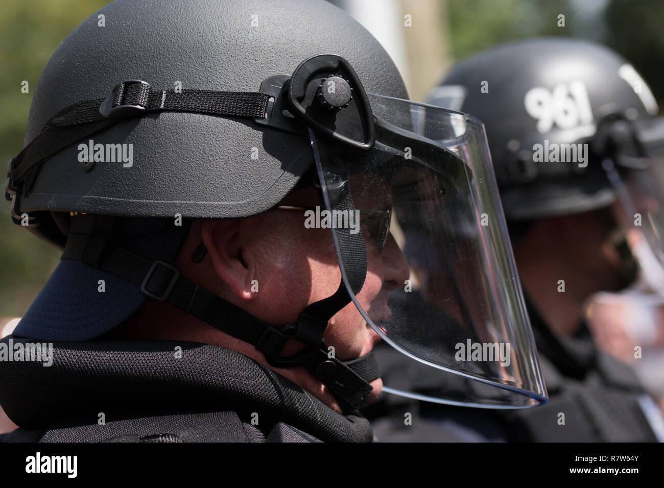 Riot police with tear gas , face shields and body armor gear up to ...