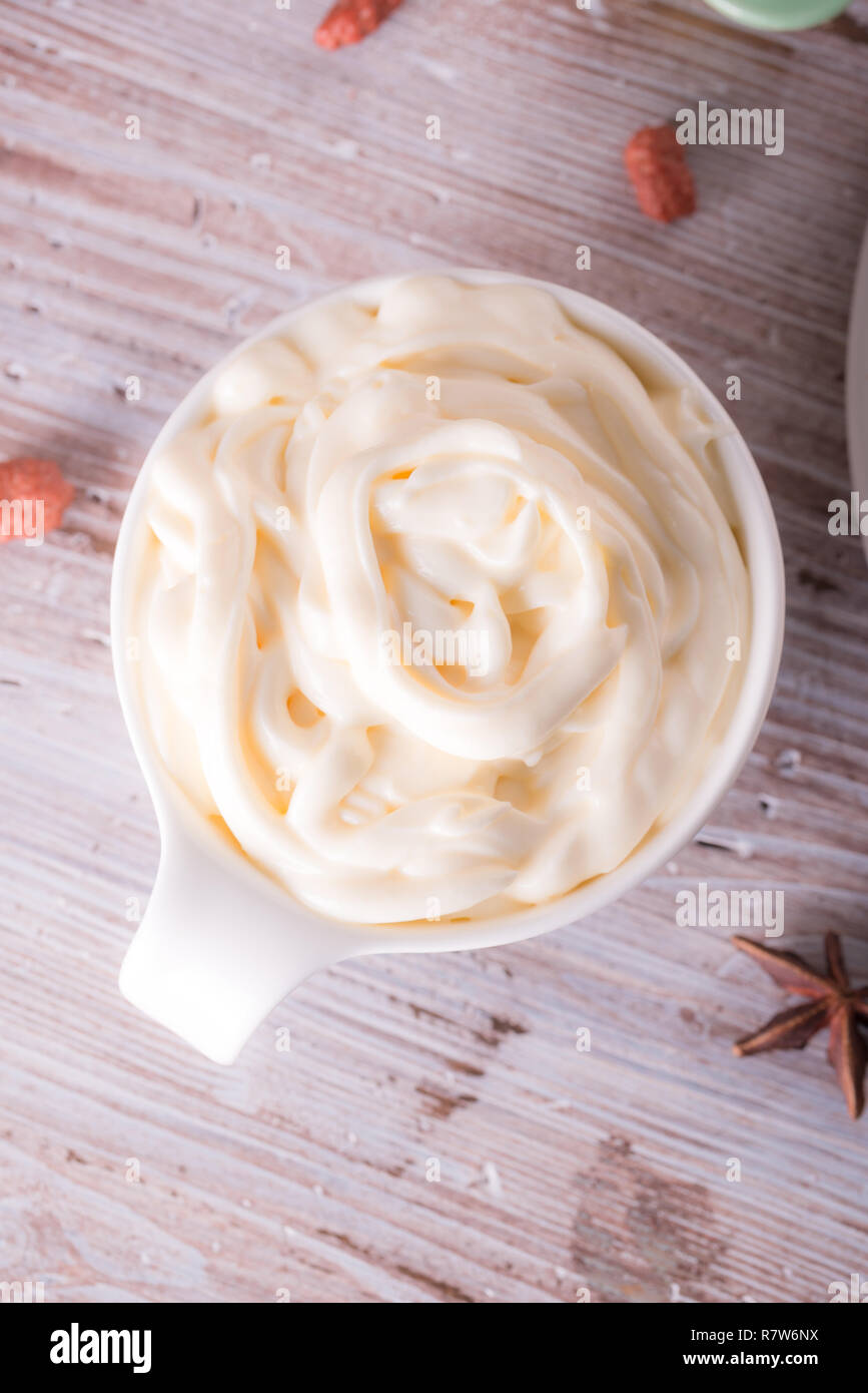 Vertical photo of white cup. Cup is fully filled by sweet curd cheese ...