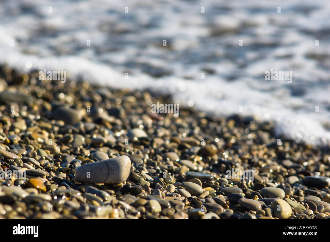 pebble stones on the sea beach, the rolling waves of the sea with foam ...